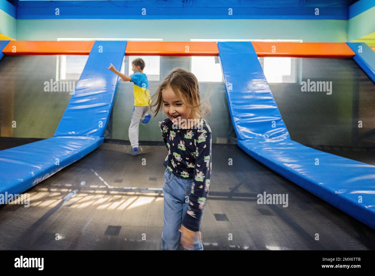 Brother with sister playing at indoor play center playground , jumping ...