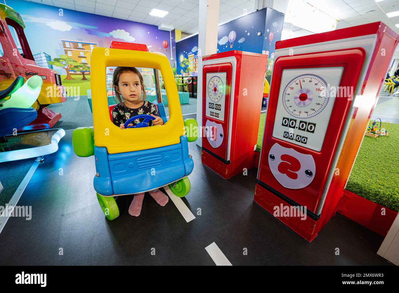 Playing at indoor play center playground , girl in toy car gas station ...