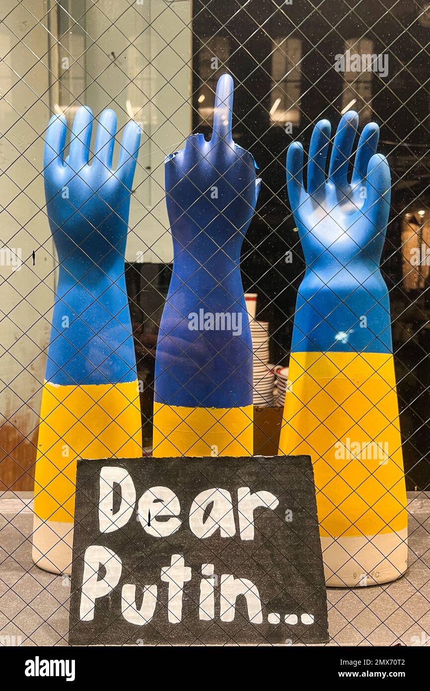 A sign in front of mannequin hands painted in the blue and yellow ...