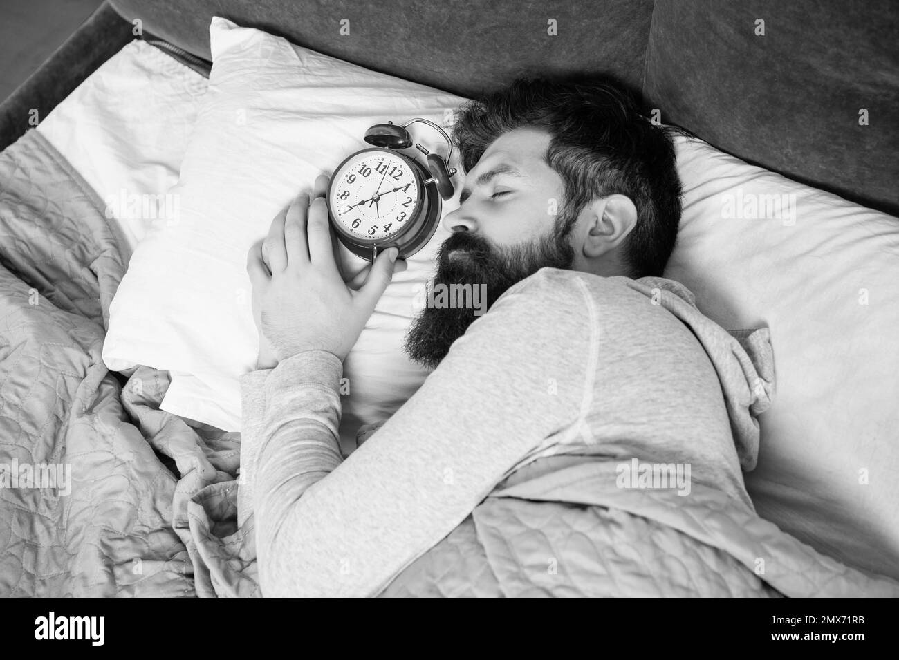 Man sleeping with alarm clock in bed, sleep time Stock Photo - Alamy