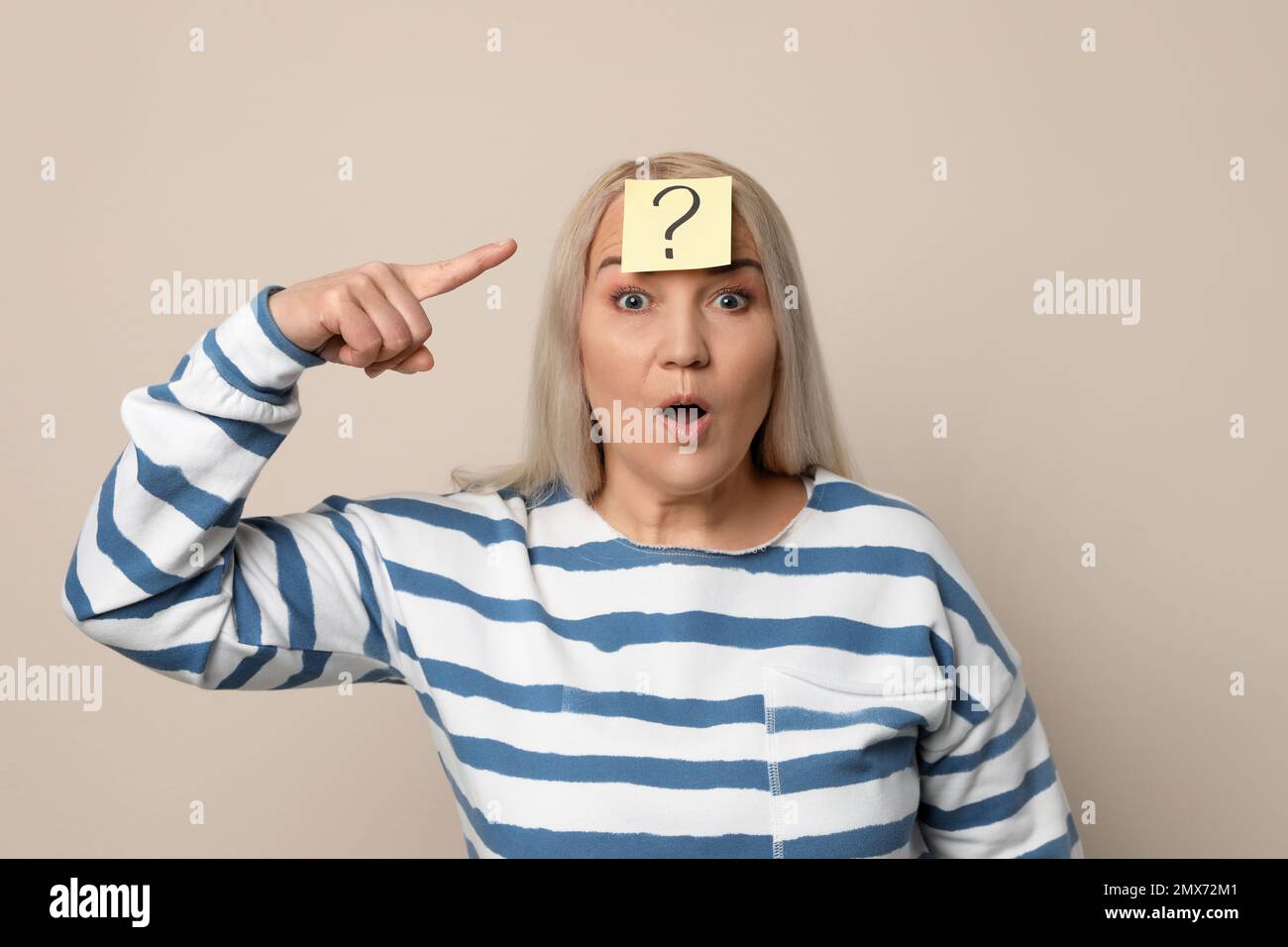 Emotional mature woman with question mark on beige background Stock ...