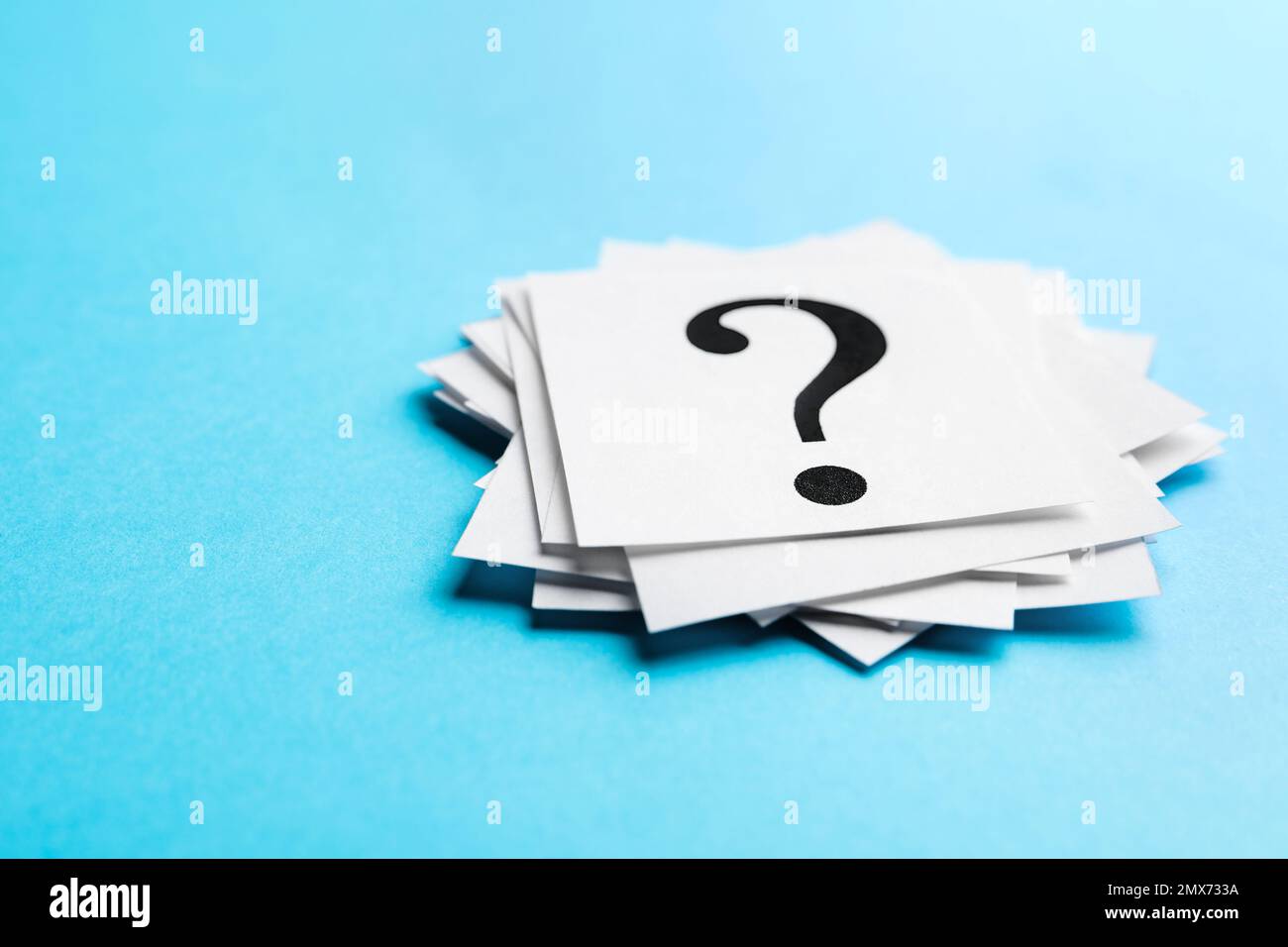 Heap of paper notes with question marks on light blue background ...
