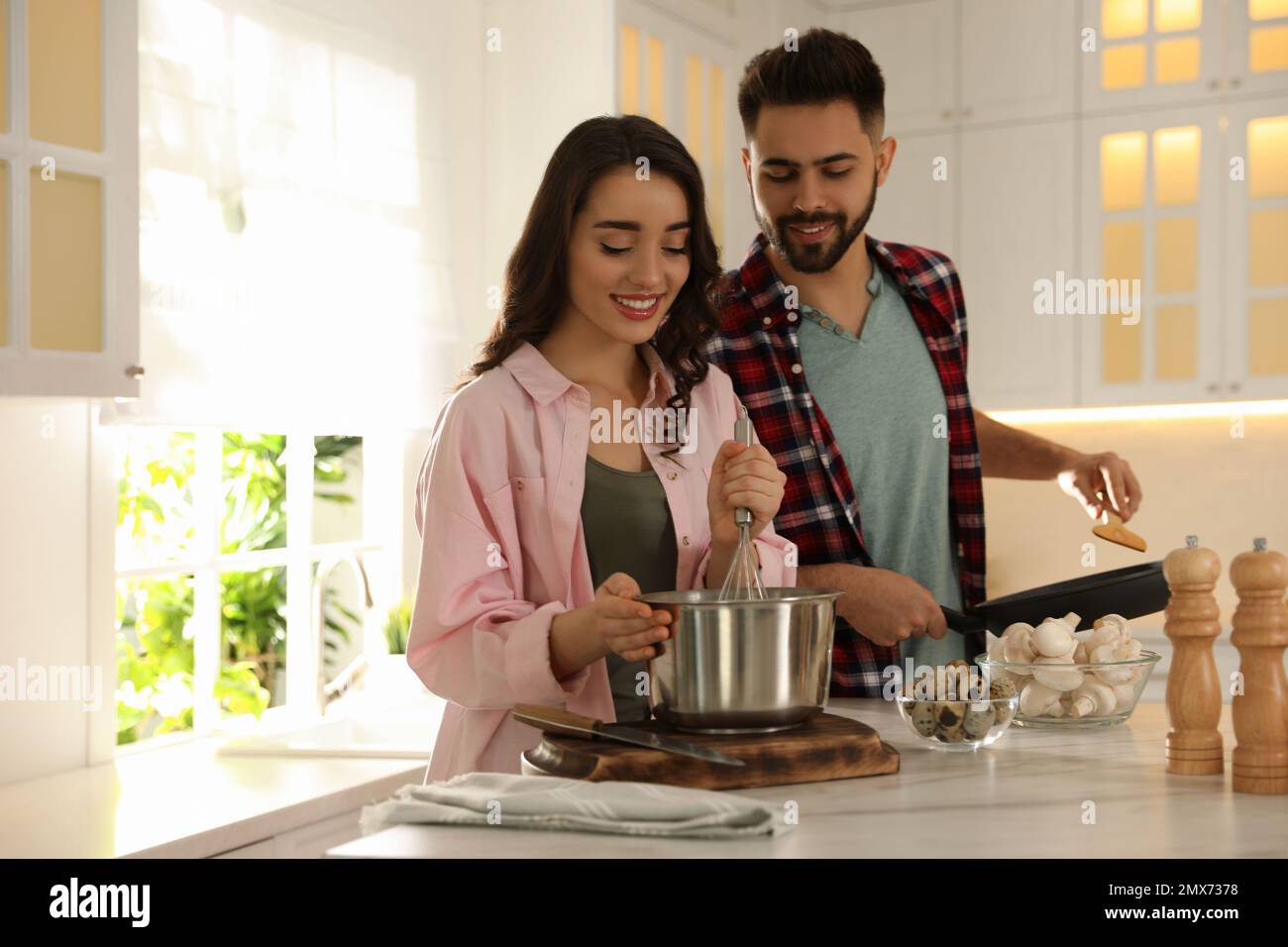 Lovely young couple cooking together in kitchen Stock Photo - Alamy