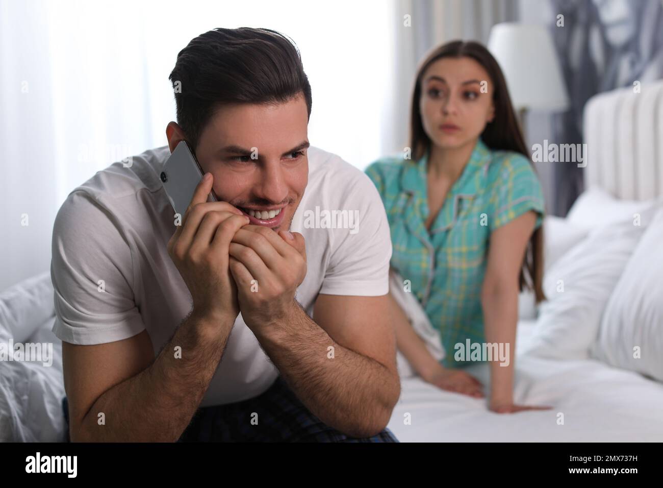 Distrustful young woman eavesdropping on boyfriend at home. Jealousy in relationship Stock Photo ...