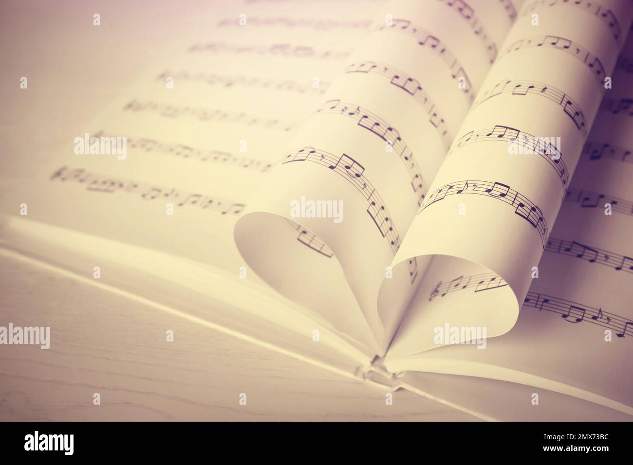 Heart made of book pages with music notes on table, space for text ...