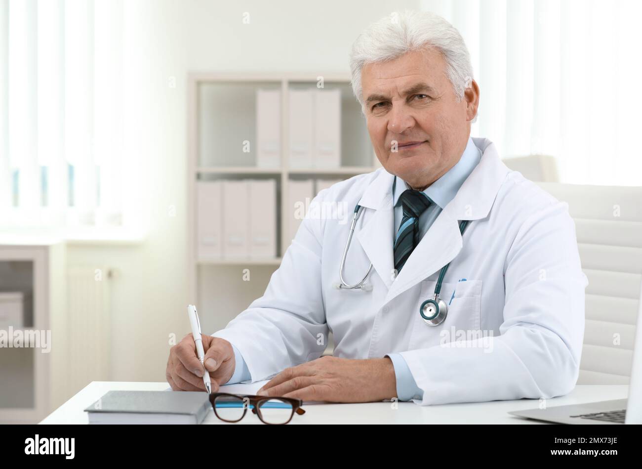 Portrait of senior doctor in white coat at workplace Stock Photo - Alamy