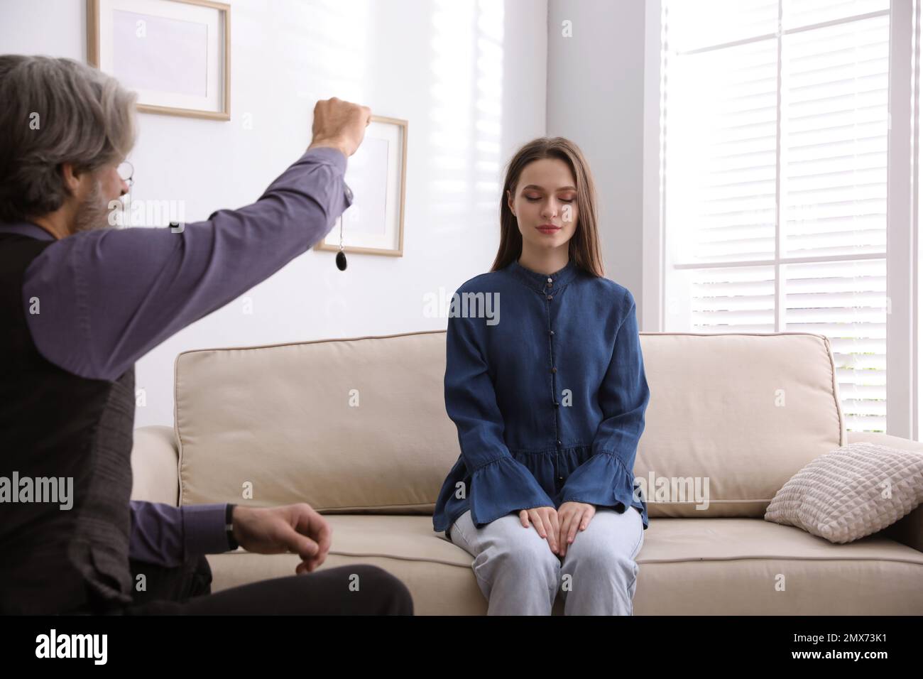 Psychotherapist using pendulum during hypnotherapy session in office ...