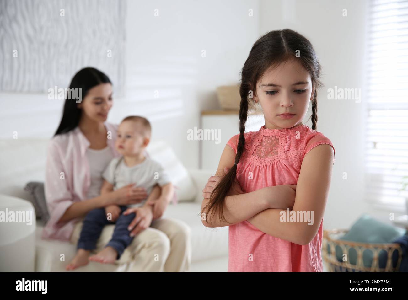 Unhappy little girl feeling jealous while mother spending time with her ...