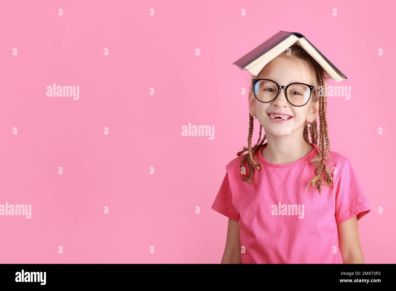 Back to school concept. Smiling pretty little school girl in glasses is ...