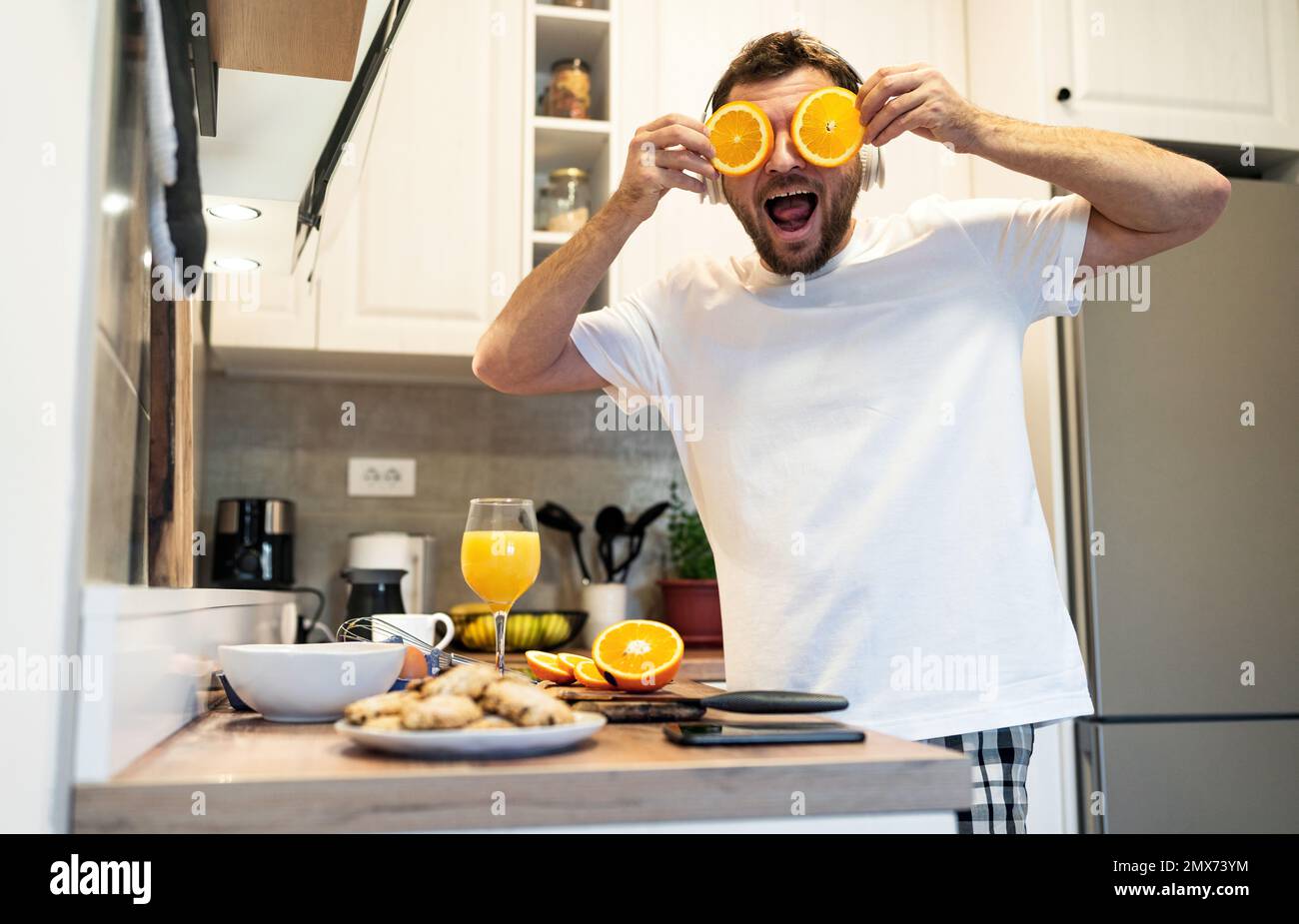 Man has fun while cooking breakfast closing his eyes with slices of ...