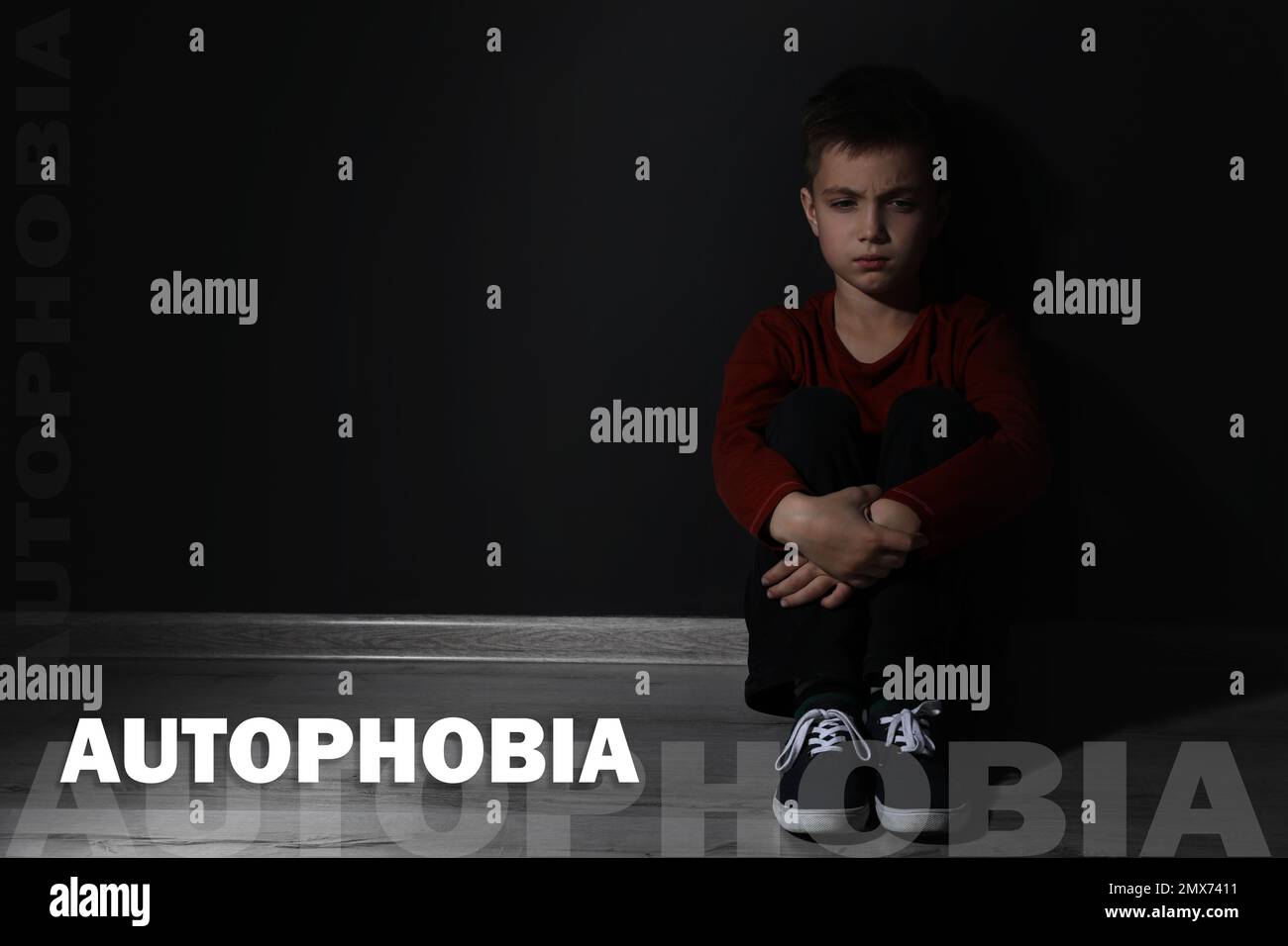 Sad little boy sitting alone near black wall, space for text ...