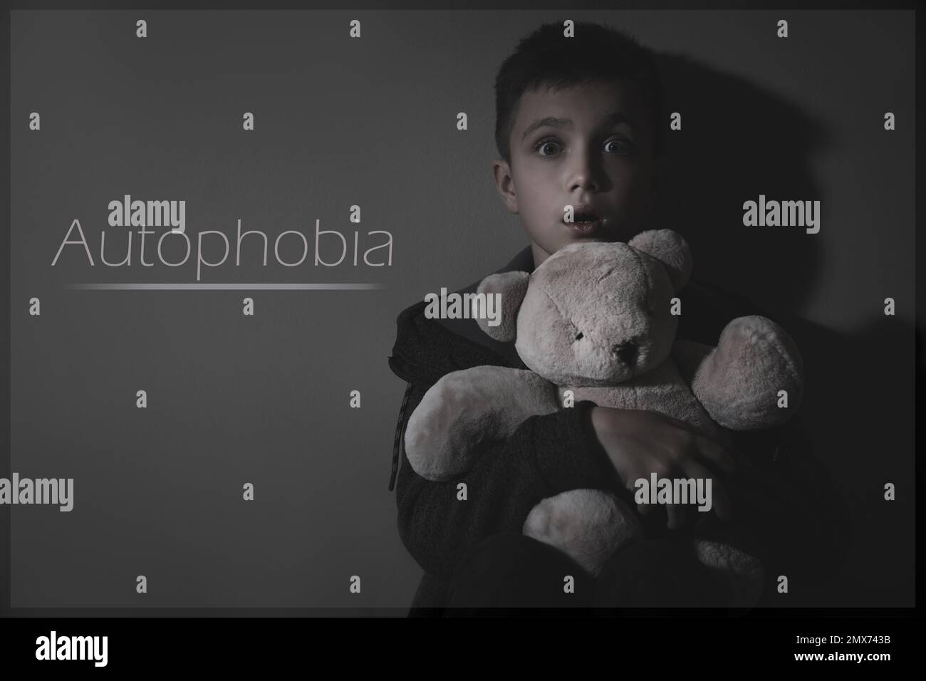 Scared little with toy near dark wall. Autophobia - fear of isolation ...
