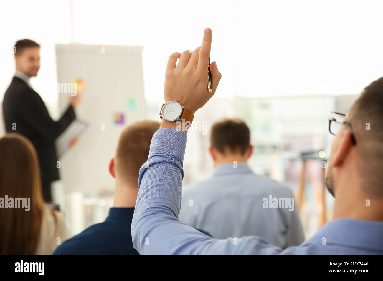 Man raising hand to ask question at business training indoors, closeup ...