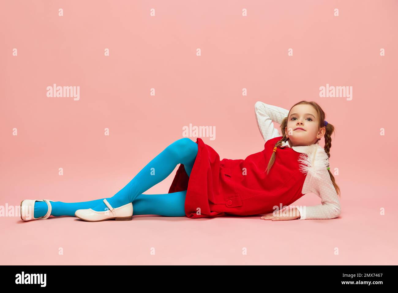 Lovely, cute, little girl, child in red dress and blue tights lying on ...