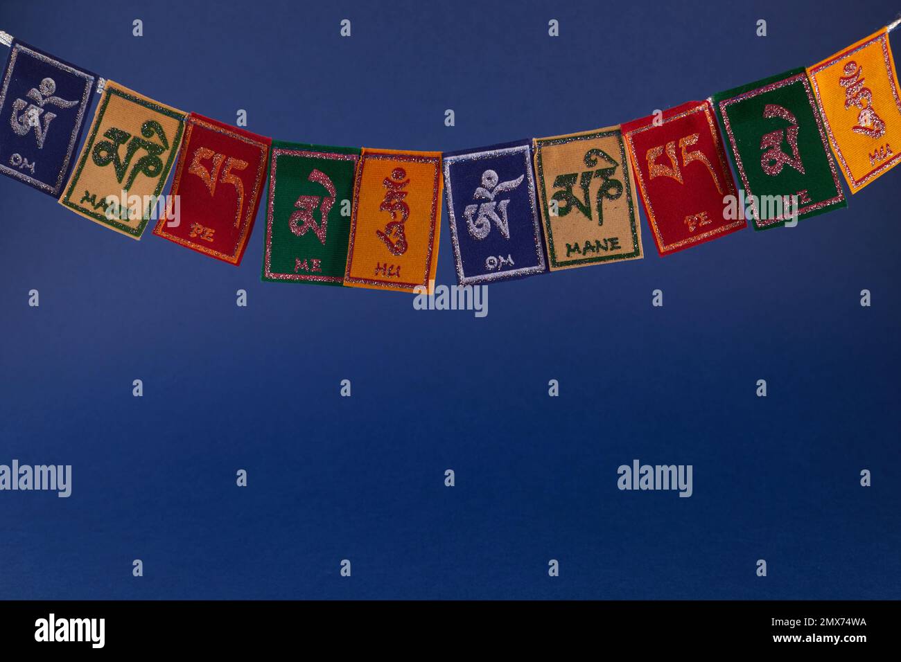 Tibetan Buddhist flags against blue background. Text on flags Om mani ...