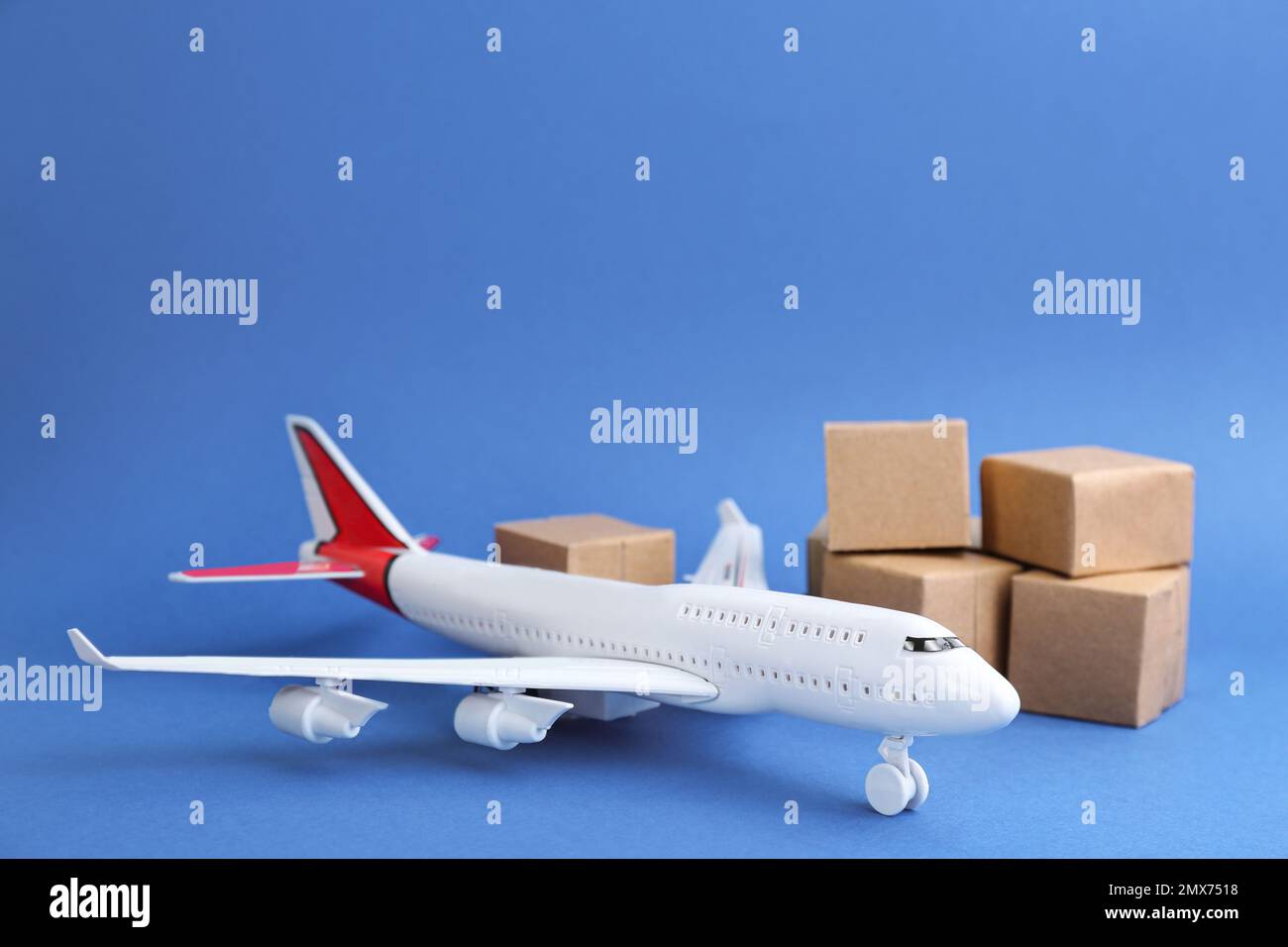 Airplane model and carton boxes on blue background. Courier service ...