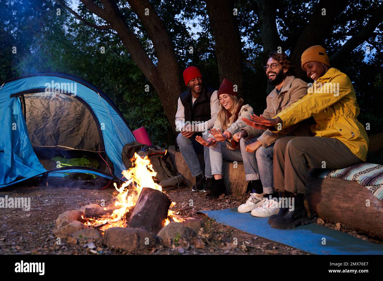 Young multiethnic group of friends camping outdoors sitting around ...
