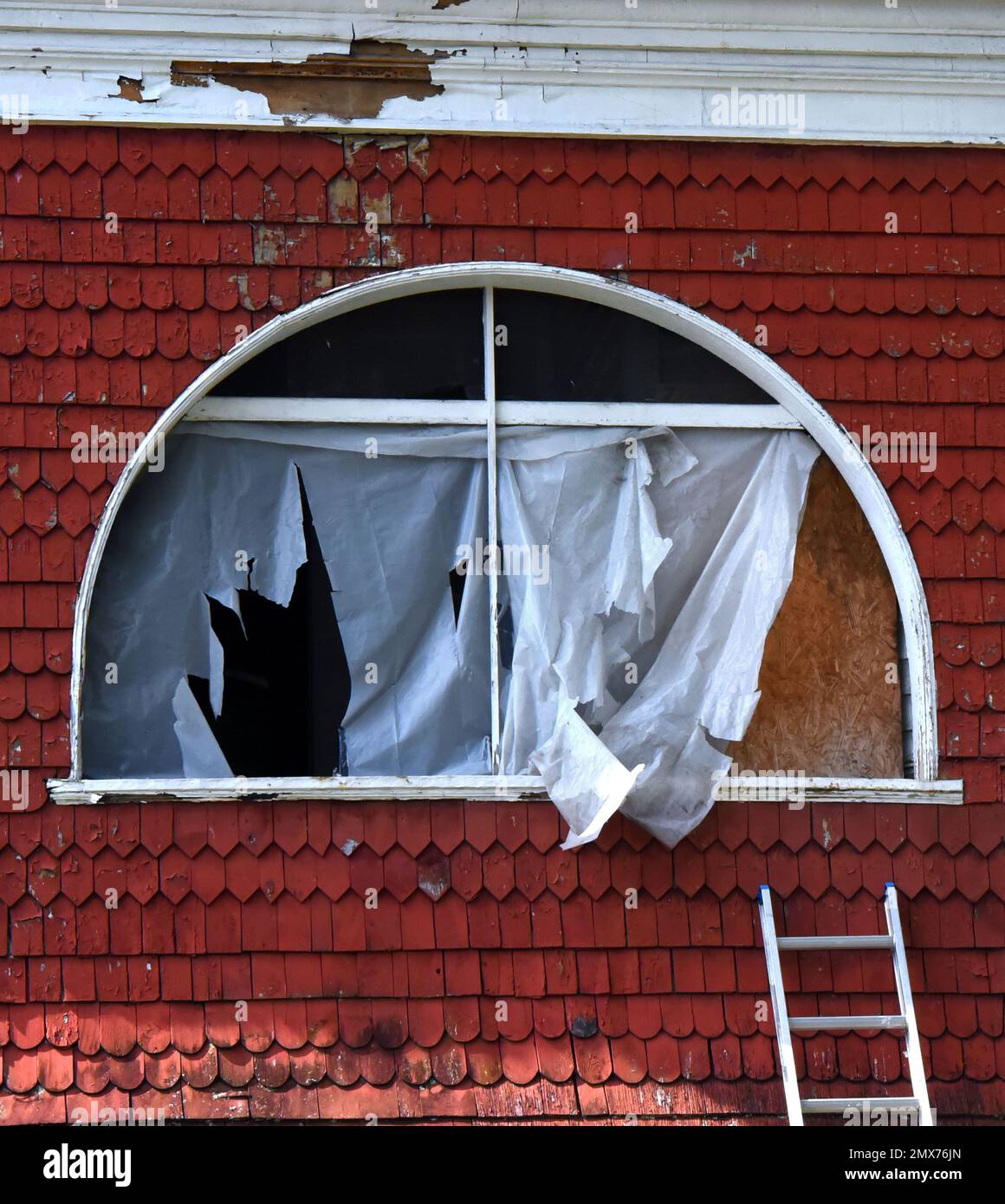 Ladder leans against an old Victorian house. It is just beneath a ...