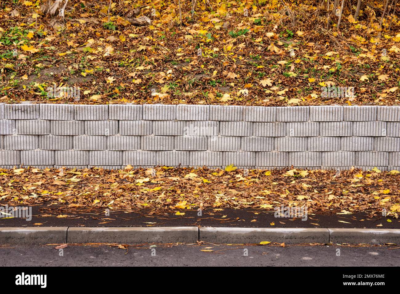 A retaining wall made of concrete elements protects the roadway and ...