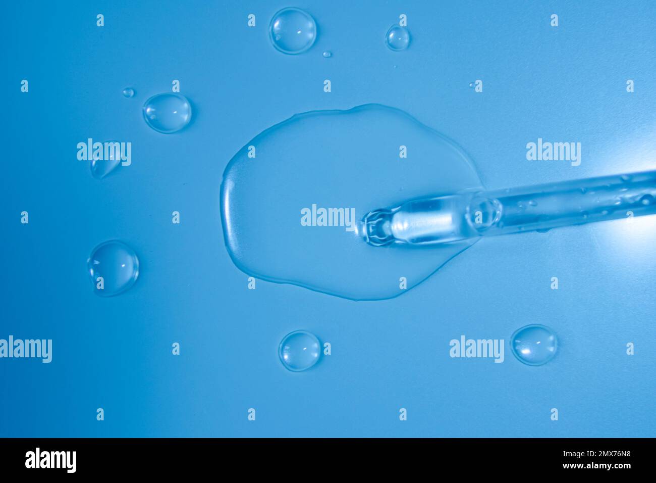 Water bubbles with cosmetic liquid drops of serum on a blue background ...