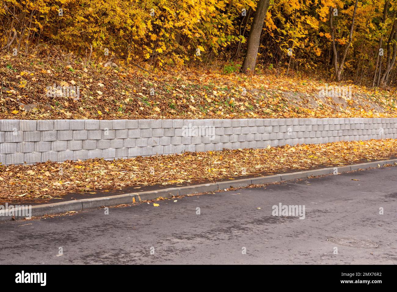 A retaining wall made of concrete elements protects the roadway and ...
