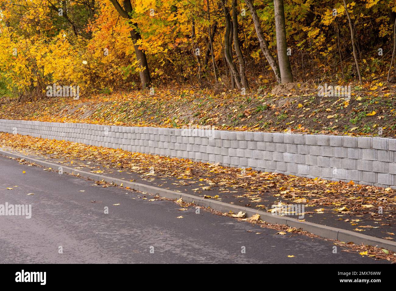 A retaining wall made of concrete elements protects the roadway and ...