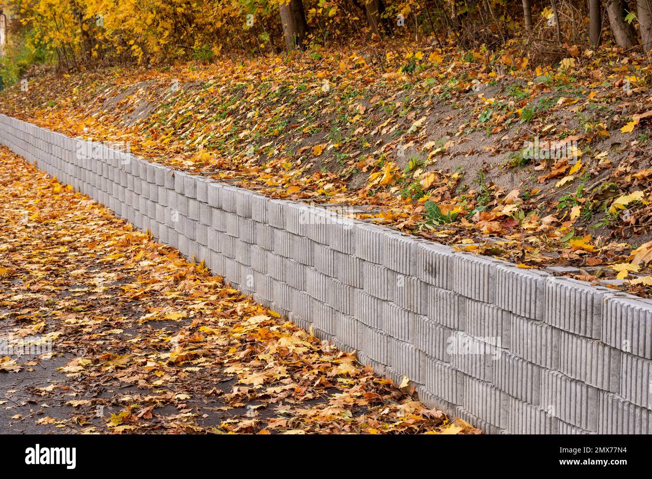 A retaining wall made of concrete elements protects the roadway and ...