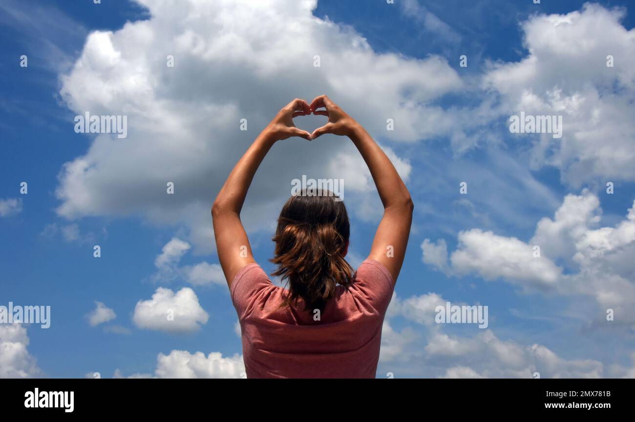 Young, female, teen forms heart shape with her hands. She is looking ...