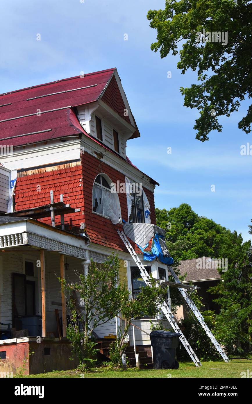 Two ladders lean against an old Victorian home. It is undergoing a ...
