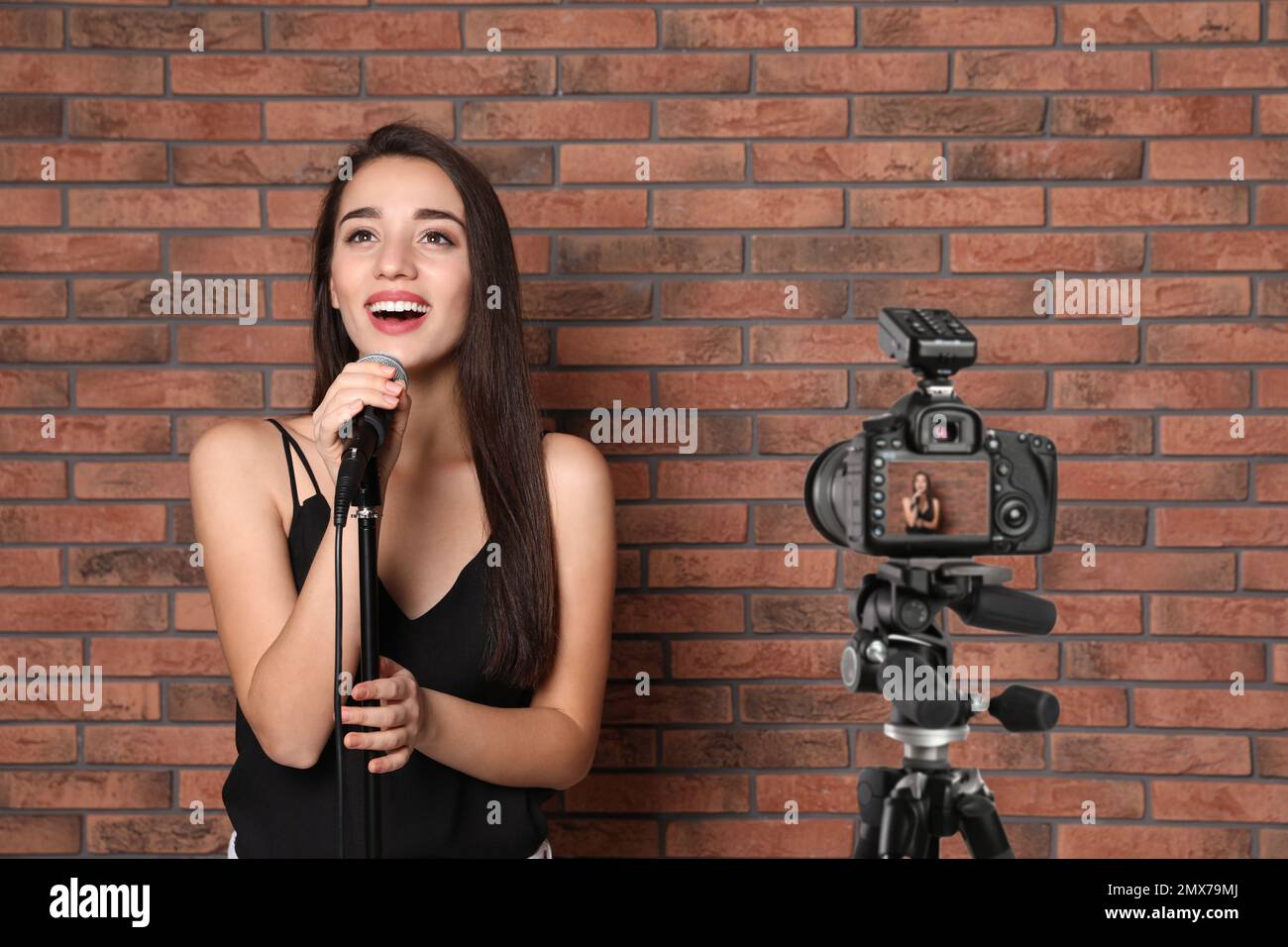 Music teacher recording singing lesson near brick wall Stock Photo - Alamy