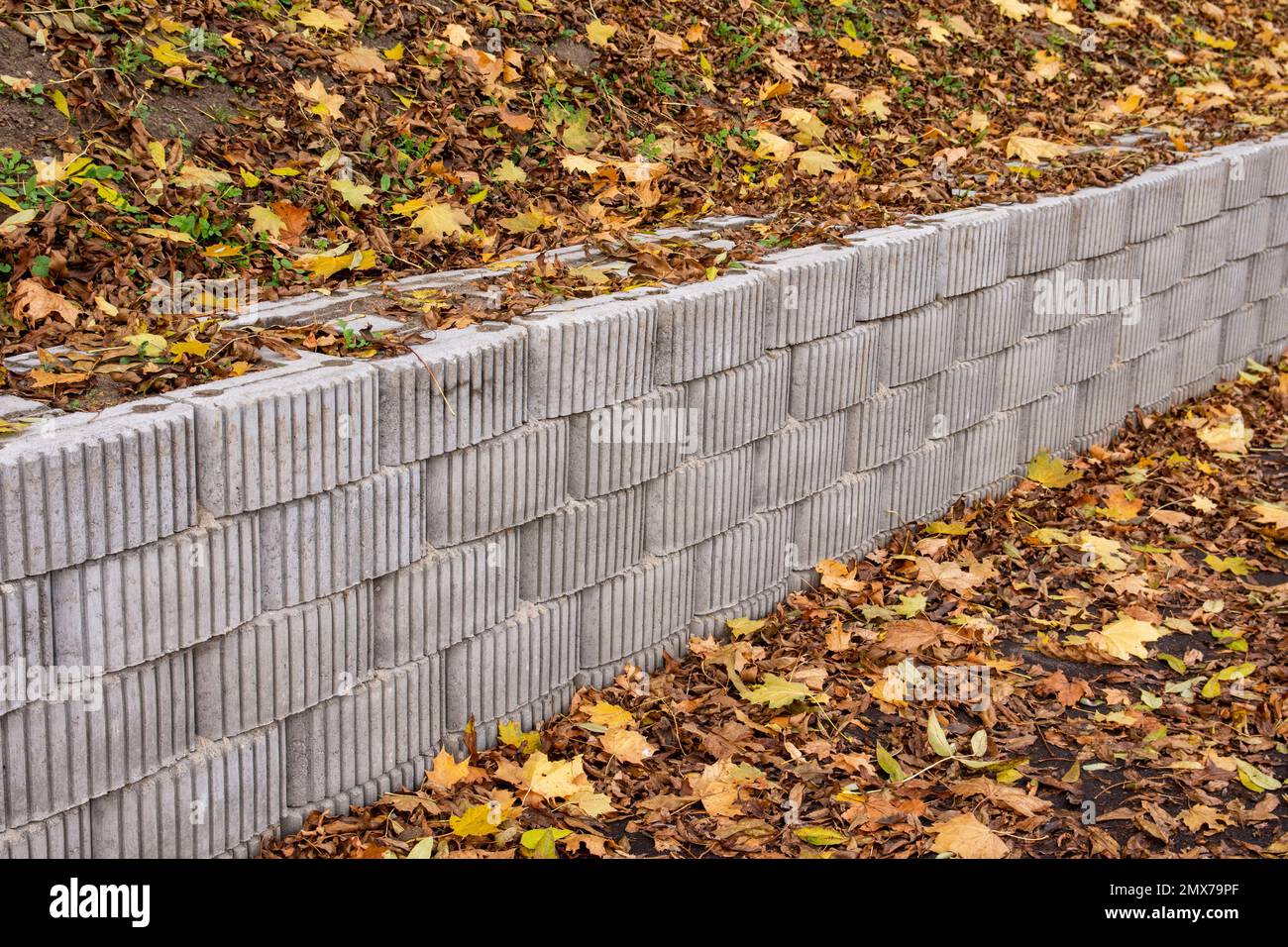 A retaining wall made of concrete elements protects the roadway and ...