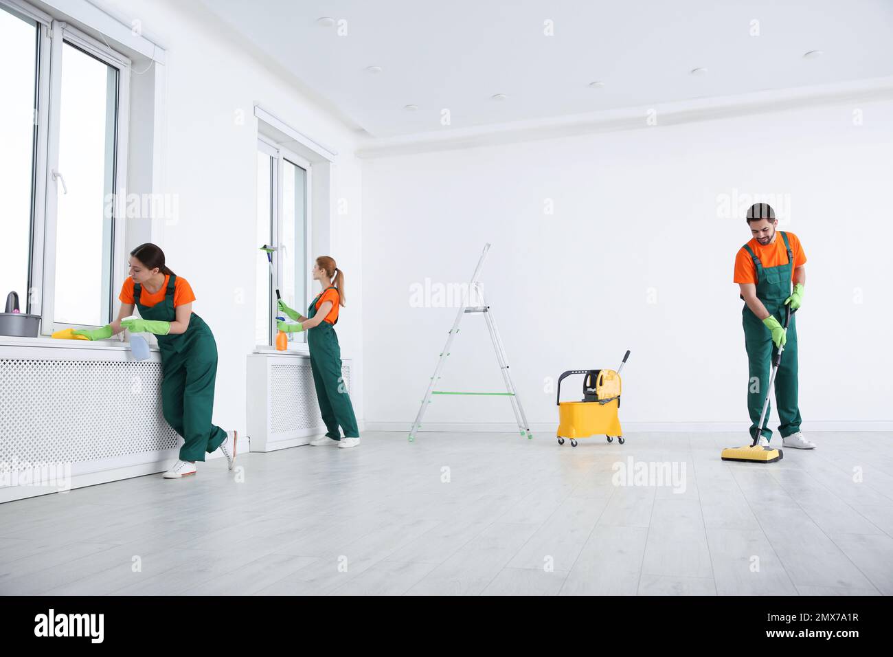 Team of professional janitors in uniforms cleaning room Stock Photo - Alamy
