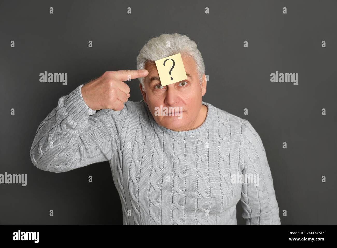 Emotional mature man with question mark on dark grey background Stock ...