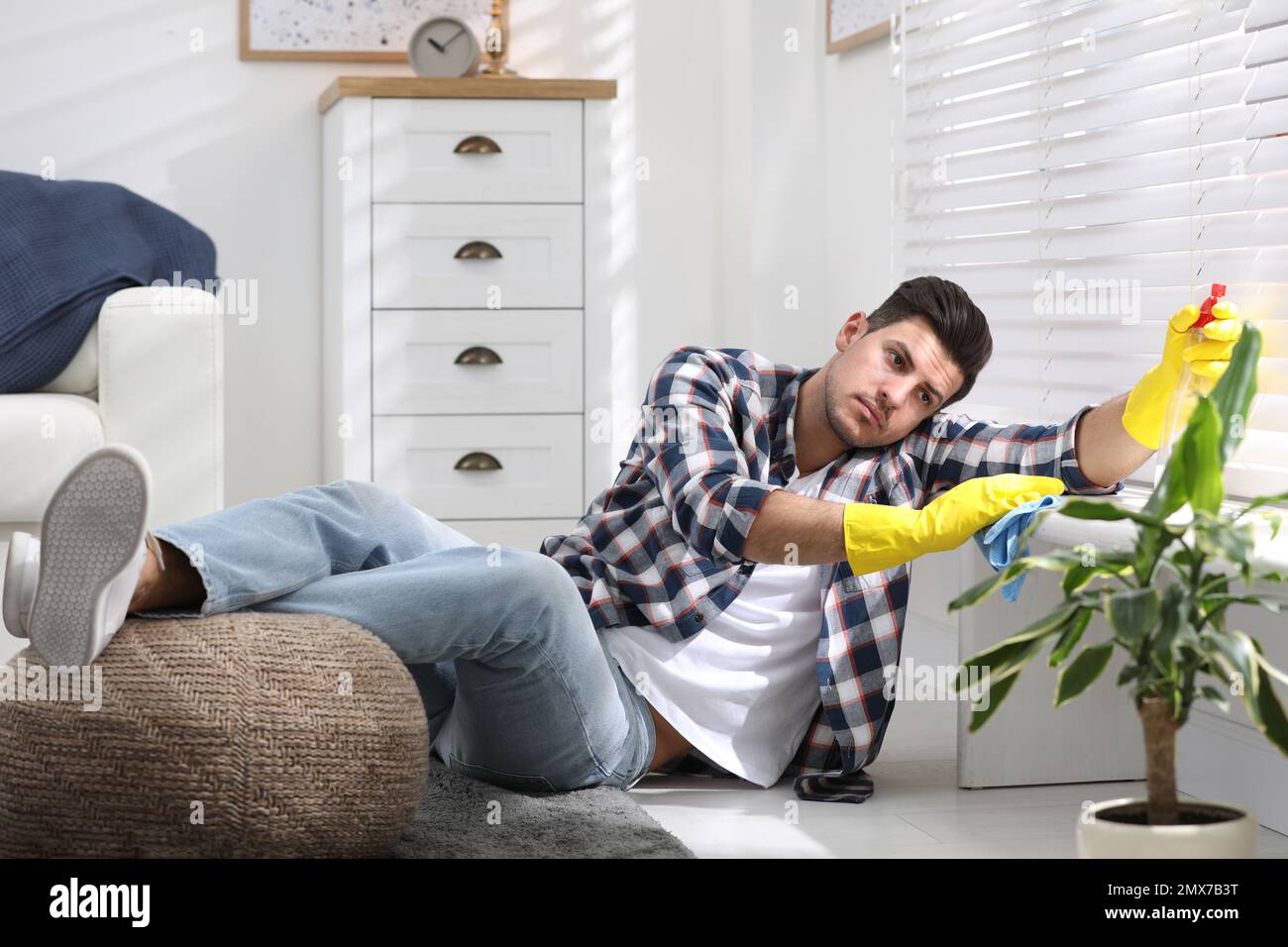 Lazy man procrastinating while cleaning at home Stock Photo - Alamy