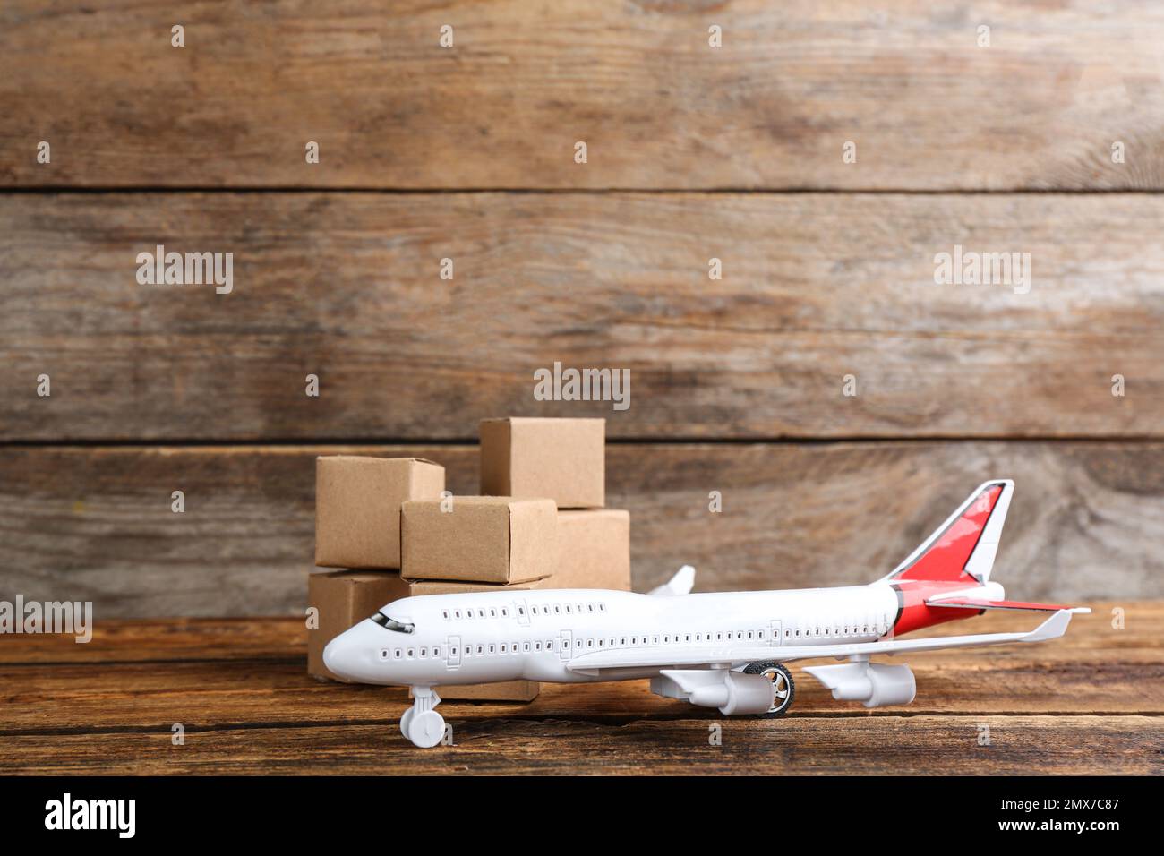 Airplane model and carton boxes on wooden background, space for text ...