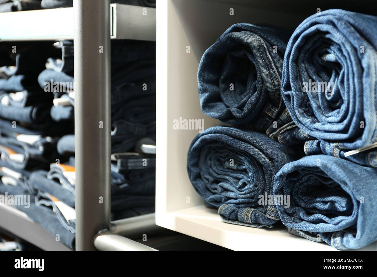 Collection of stylish jeans on shelves in shop Stock Photo - Alamy