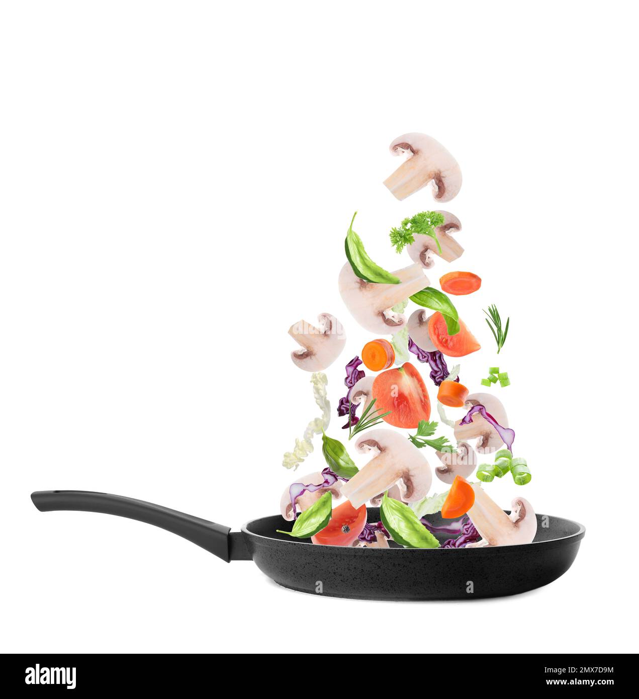 Different vegetables and mushrooms falling into frying pan on white ...