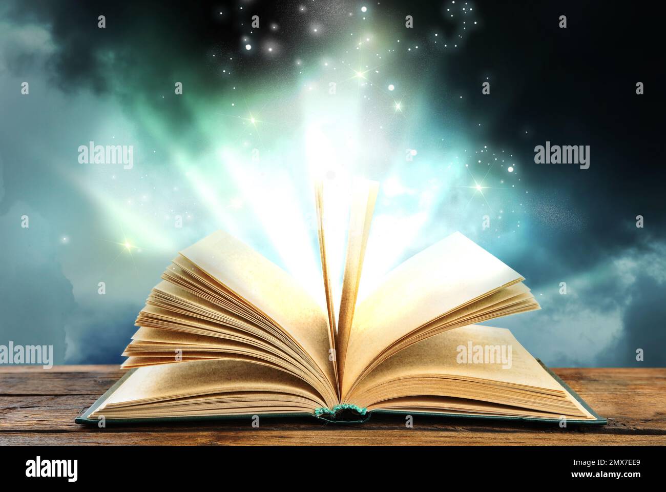Magic light emanating from open old book on table Stock Photo - Alamy
