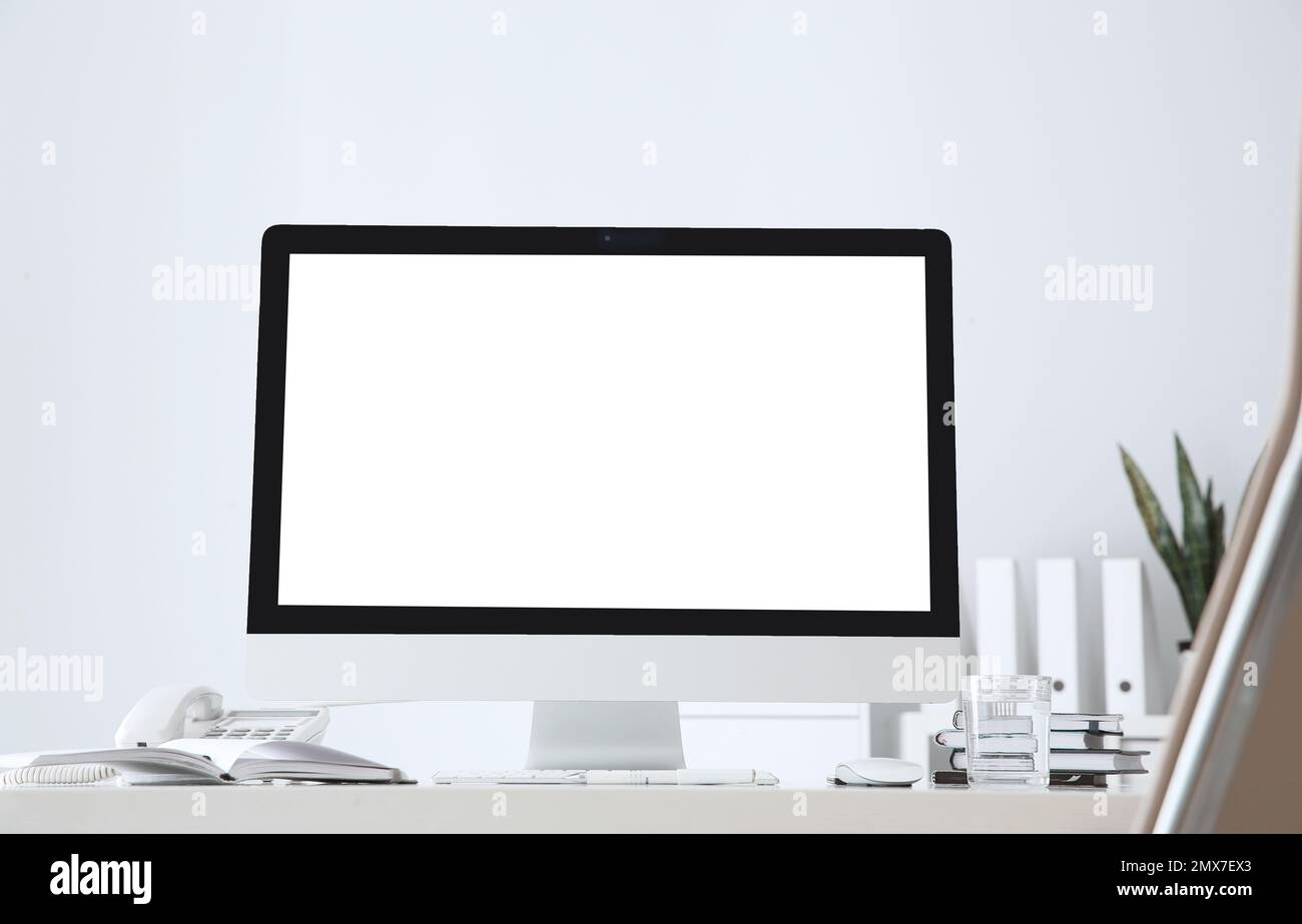 Modern computer with blank screen on table near white wall. Space for ...
