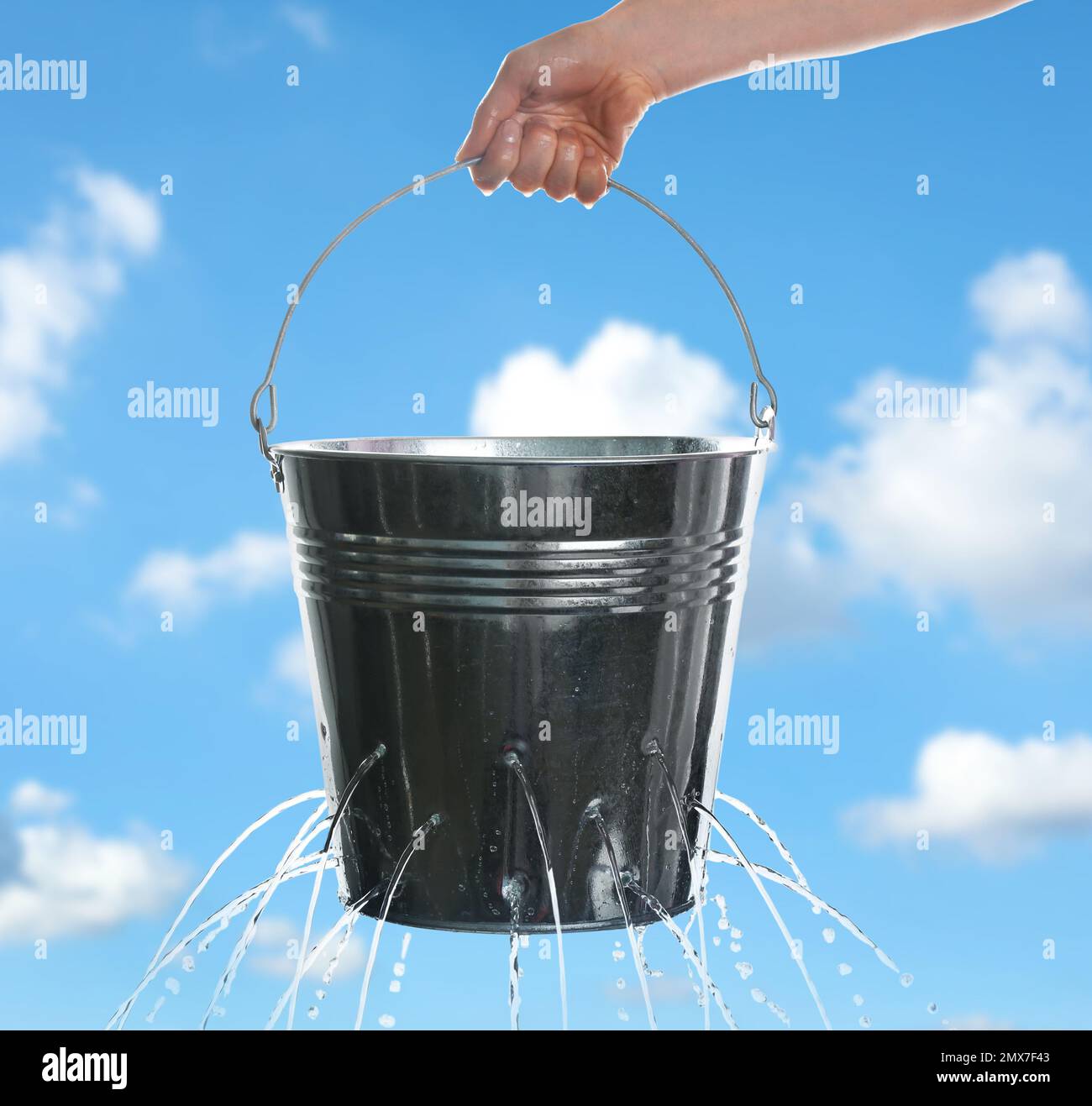 Woman holding leaky bucket with water against blue sky, closeup Stock ...
