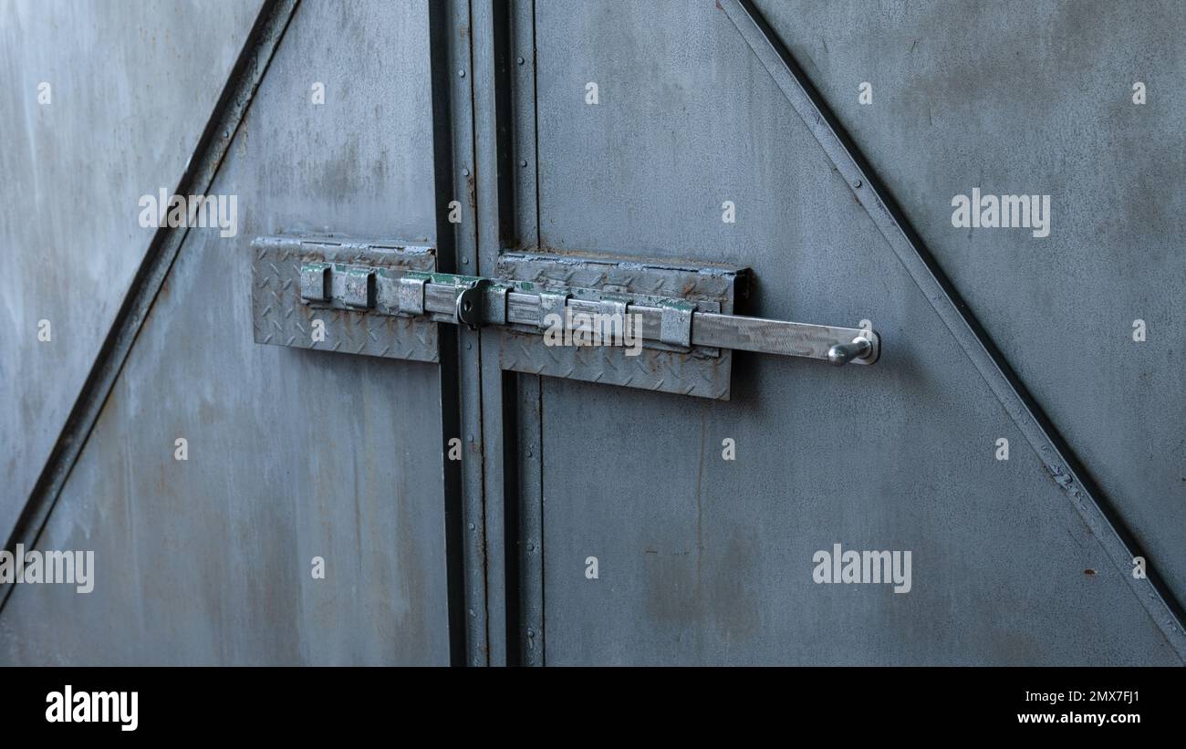 Old gray metal gate with a deadbolt. The bolt is locked. Traces of ...