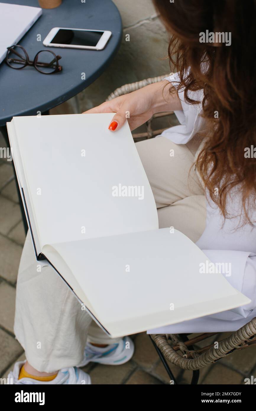 Mockup image magazine book. The girl at the coffee shop table reading ...