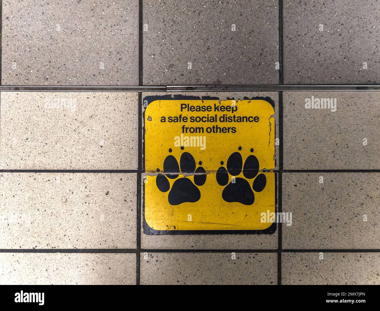 A worn social distancing sticker on the floor of a platform in the ...