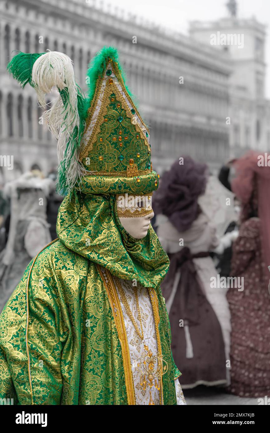Venice carnival. A person in a green richly embroidered green carnival ...