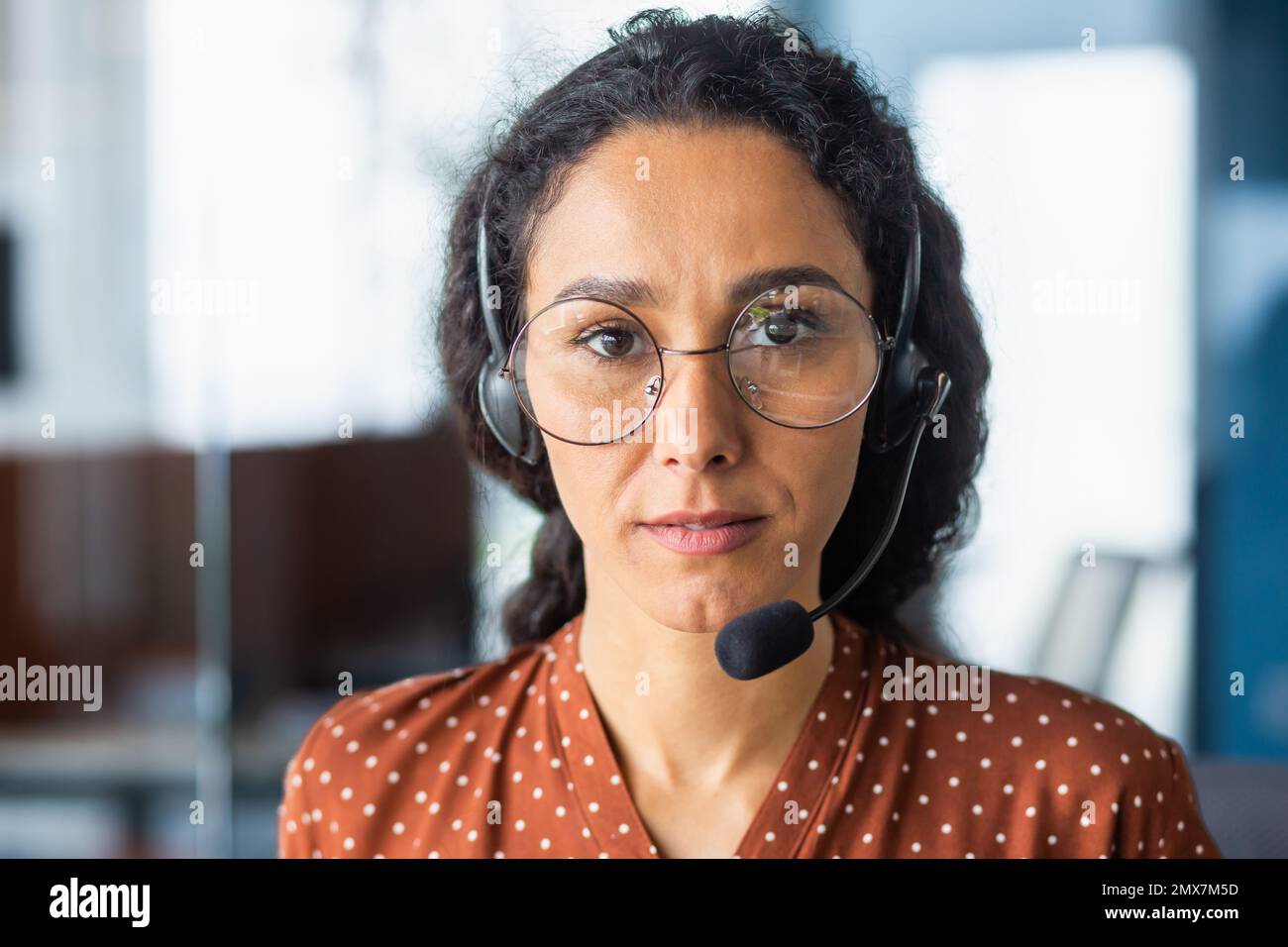 Serious and concentrated woman with video call headset looking at ...