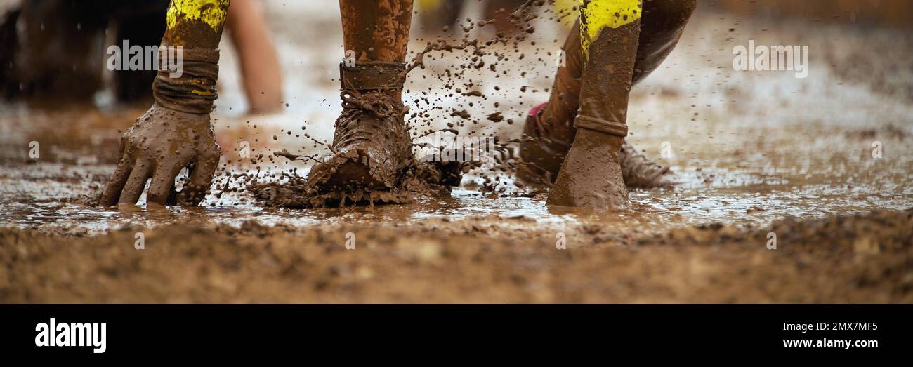 Mud race runners. Crawling,passing under a barbed wire obstacles during ...