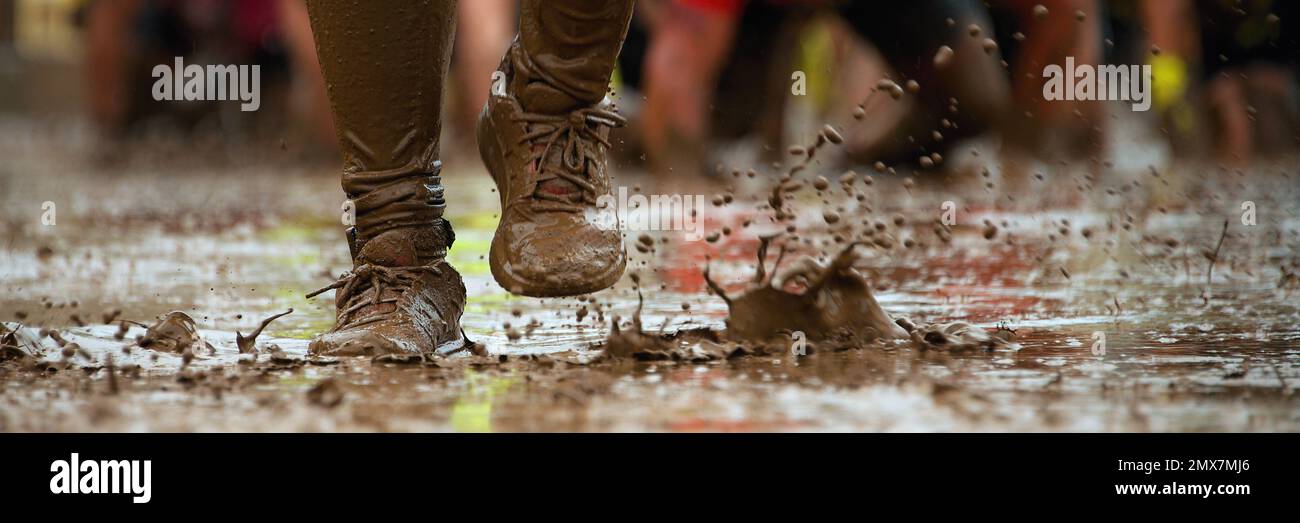 Mud race runners.Crawling,passing under a barbed wire obstacles during ...
