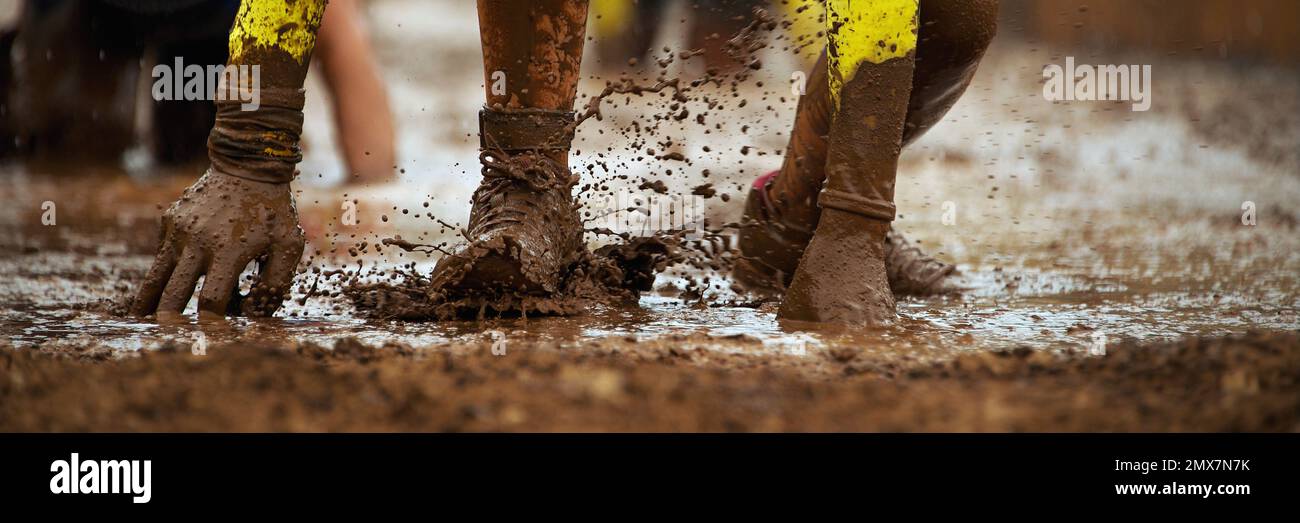 Mud race runners.Crawling,passing under a barbed wire obstacles during ...