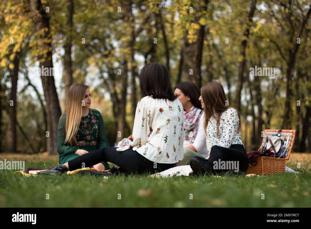 Group of four women on a fun fall picnic in the park, having a good ...
