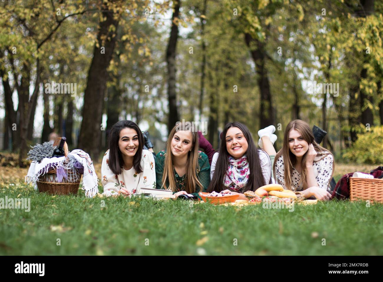 Group of four women on a fun fall picnic in the park, having a good ...